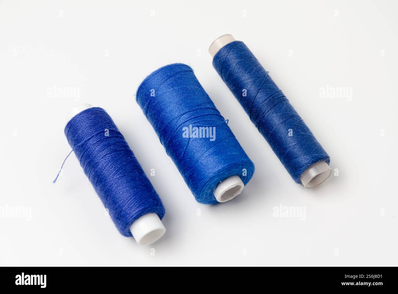 Blue thread spools on white background Stock Photo - Alamy