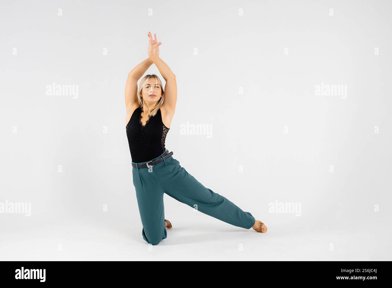 Young female dancer is kneeling on the floor raising her arms and ...