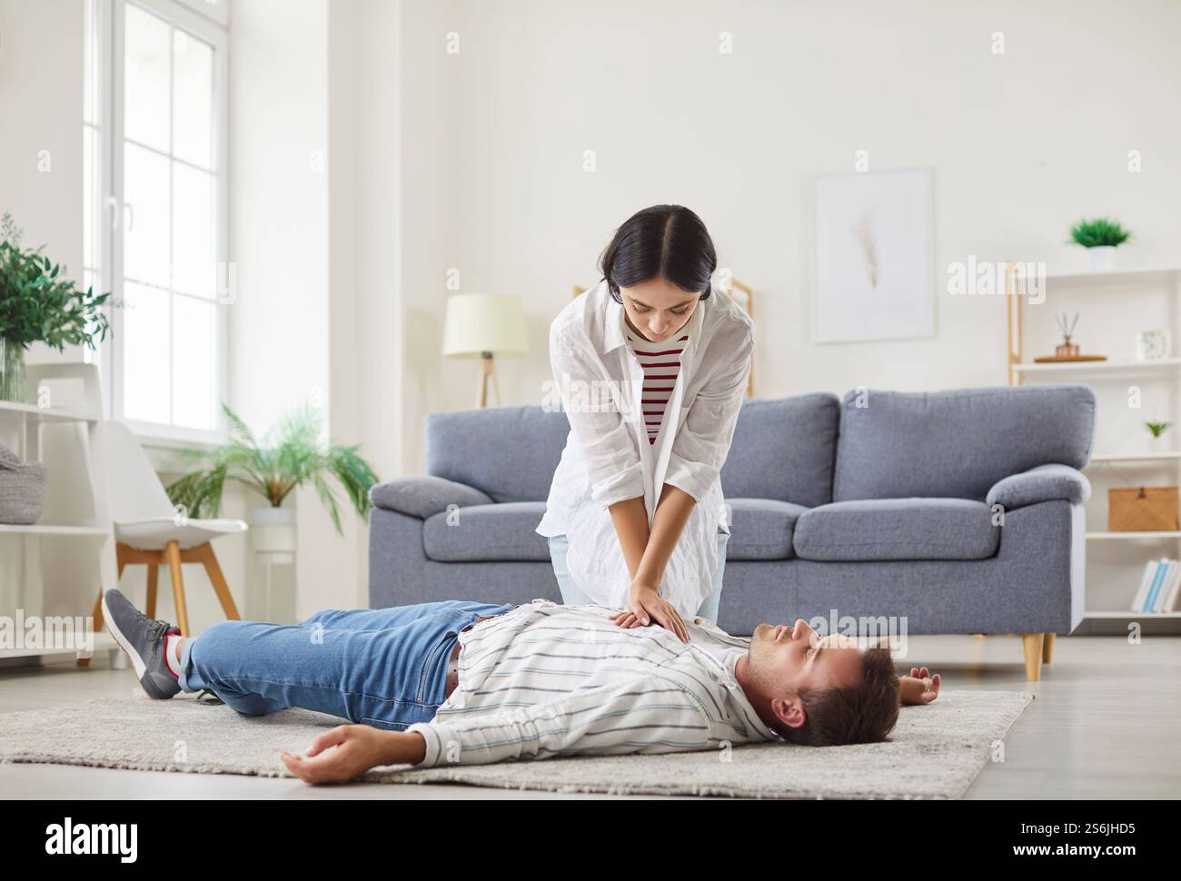 Young woman doing CPR on unconscious man lying on the floor at home Stock Photo - Alamy