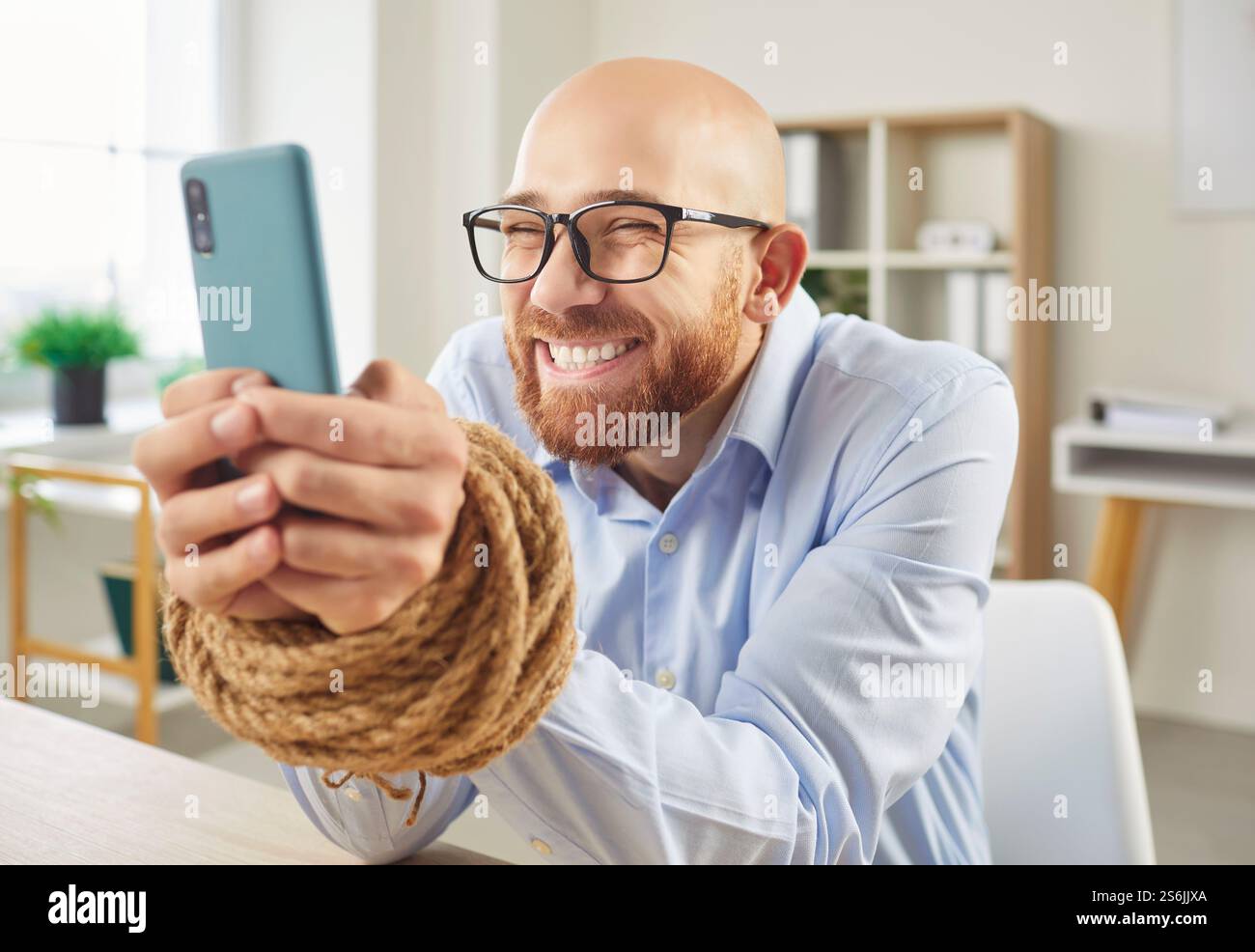 Office male employee hands connected with rope, cord to smartphone ...