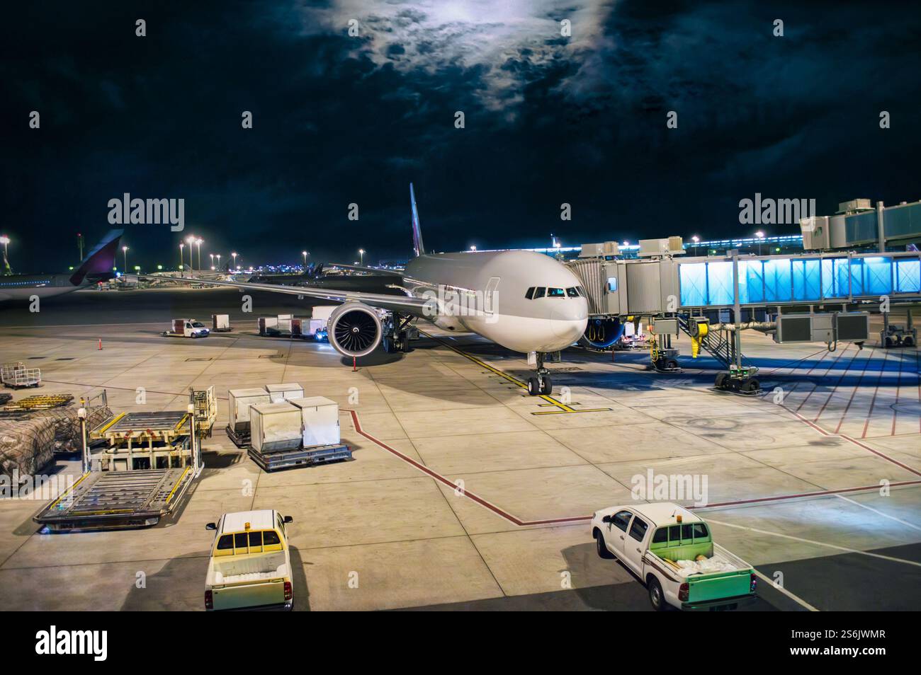 airport cargo terminal at night, plane getting loaded with containers ...