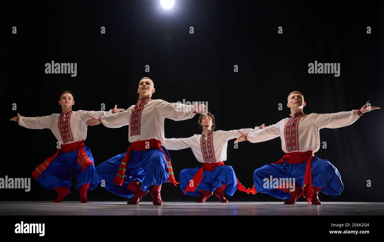 Group of male dancers performing synchronized jump, dressed in ...