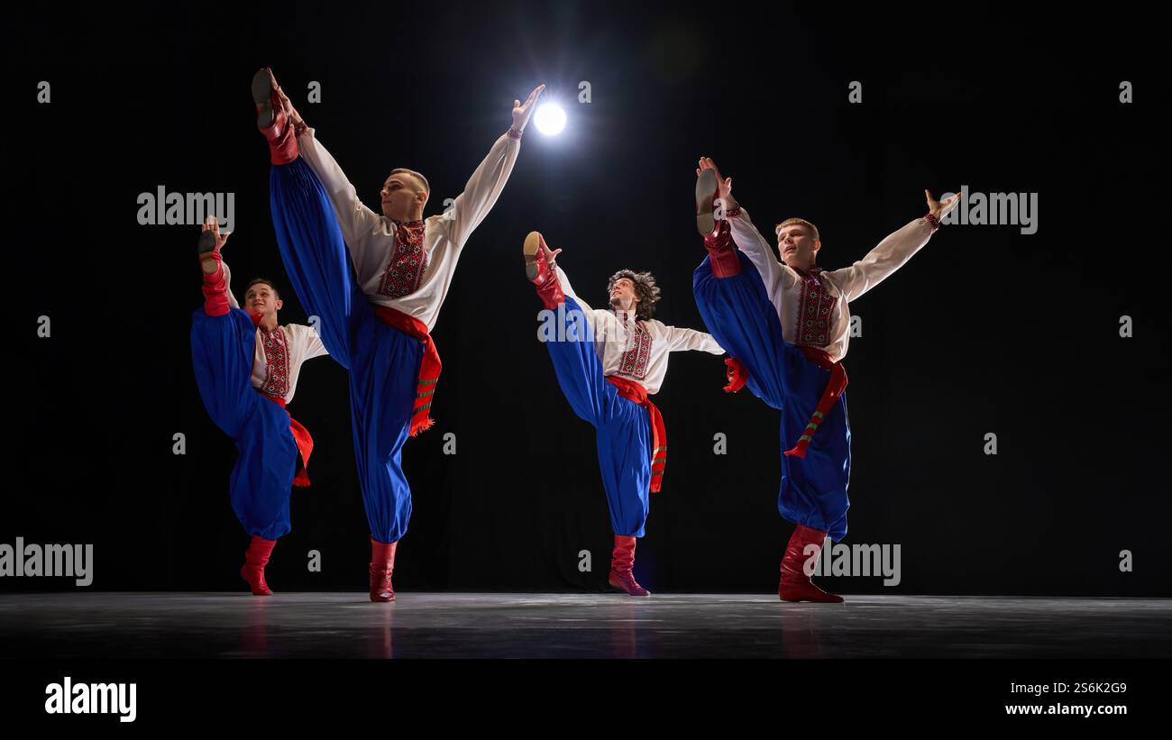 Male dancers in powerful high kick pose, wearing embroidered shirts ...