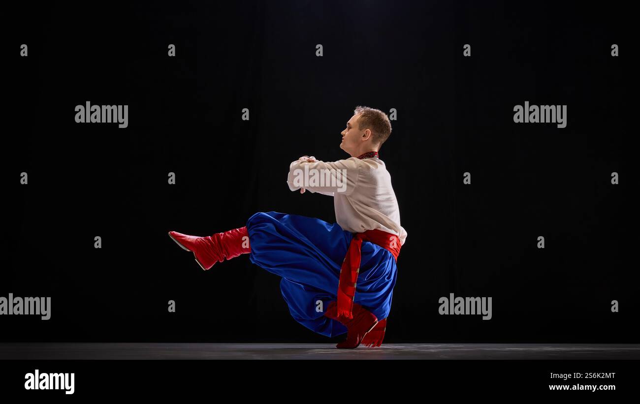 Male dancer in deep squat with one leg extended, arms elegantly ...