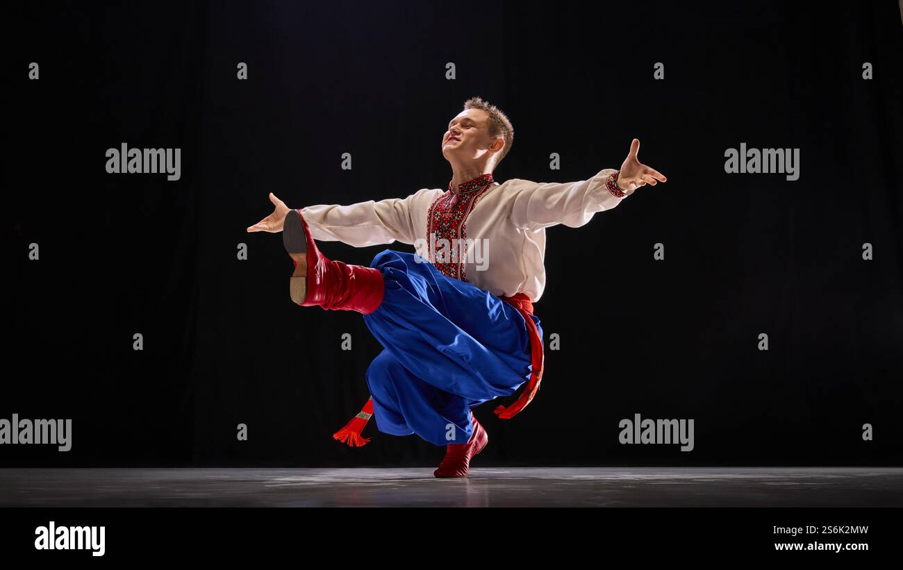 Male dancer holding balanced kick, arms wide for elegance, traditional ...