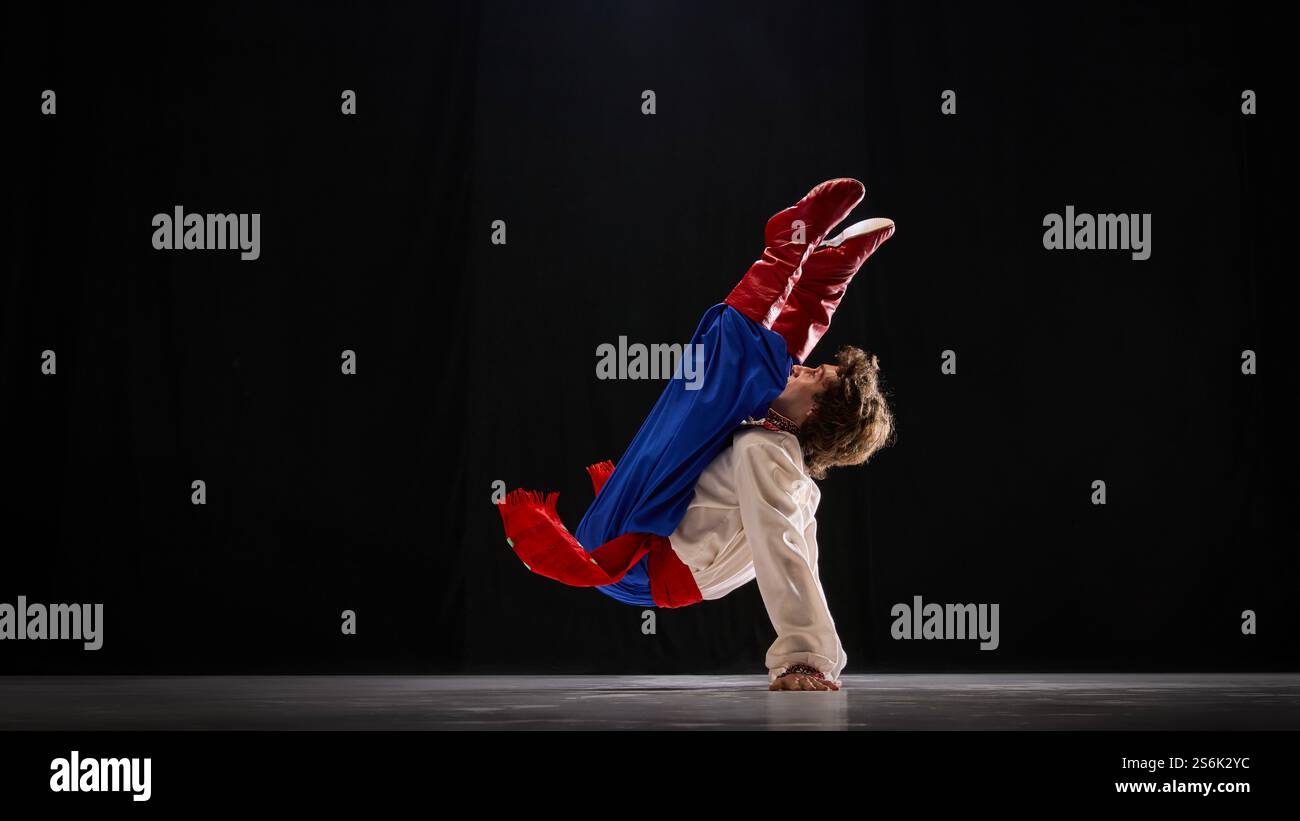 Male performer mid-air in dynamic pose, traditional embroidered attire ...