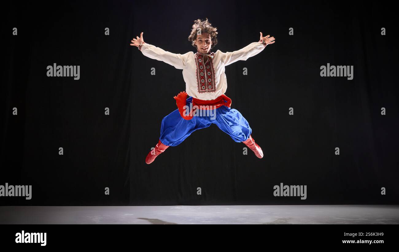 Dancer in embroidered shirt and blue Ukrainian folk attire, jumping ...