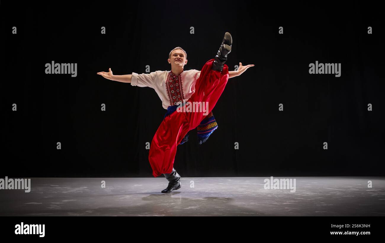Dancer in traditional attire finishes with high kick, arms open in ...