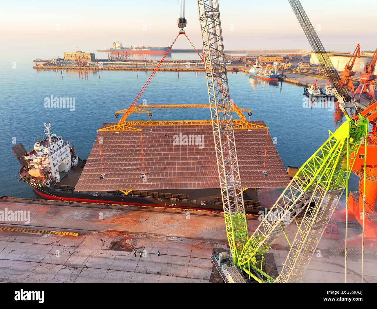 A crane lifts a large steel truss offshore photovoltaic platform onto a ...