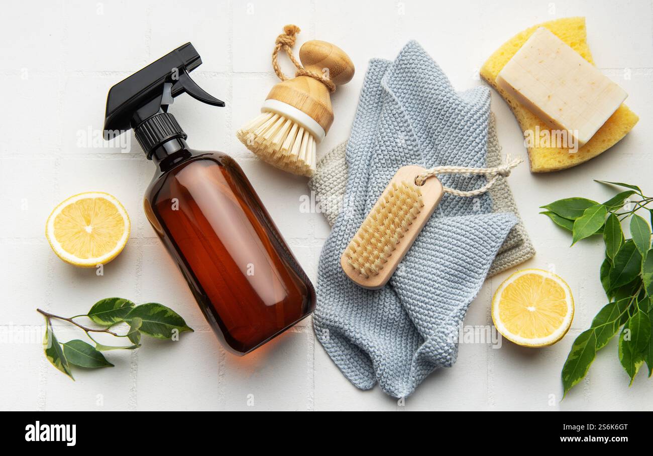 Natural cleaning products and tools arranged on a white tile background ...