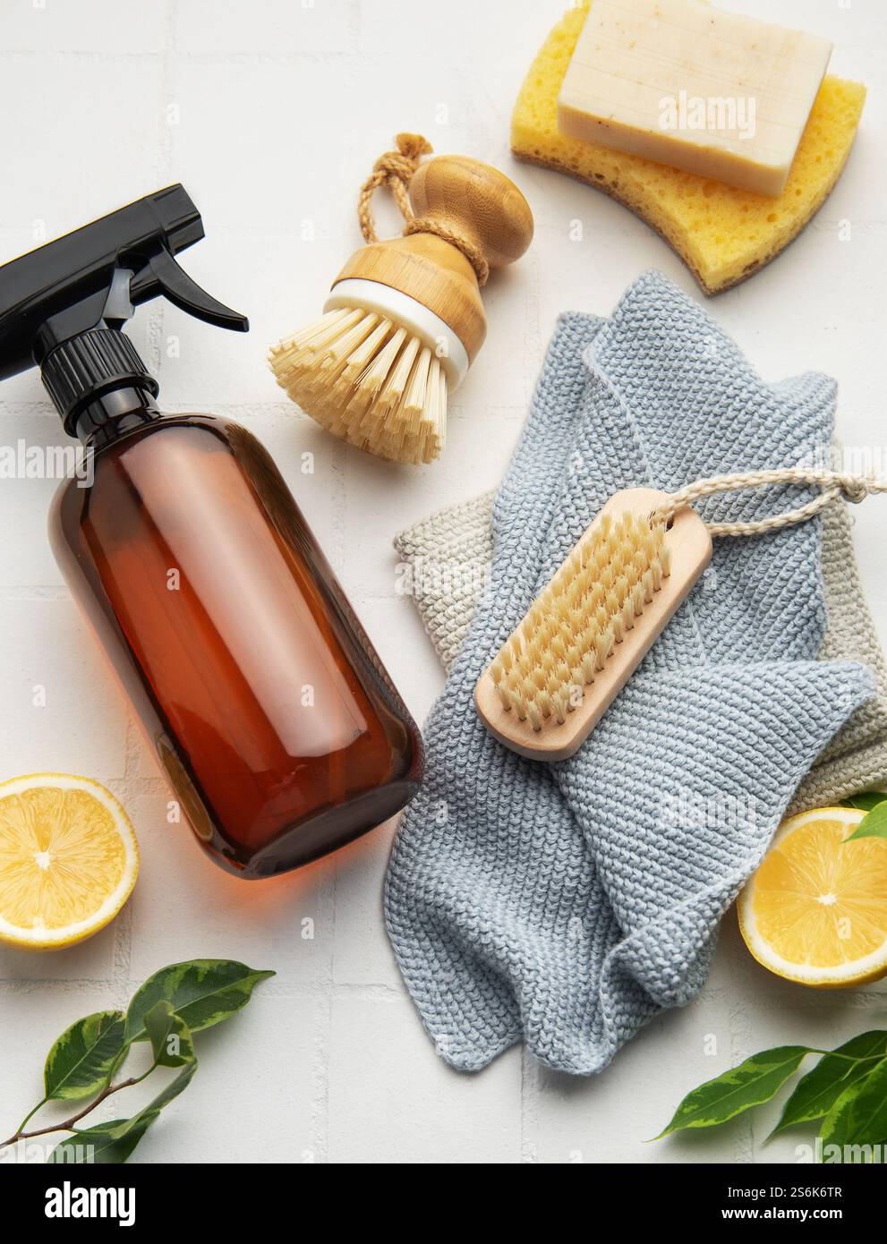 Natural cleaning products and tools arranged on a white tile background ...
