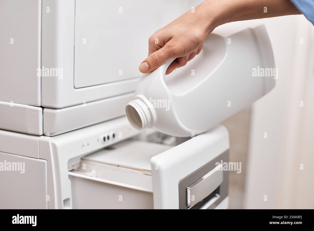 female hand pouring liquid laundry detergent from bottle into washing ...
