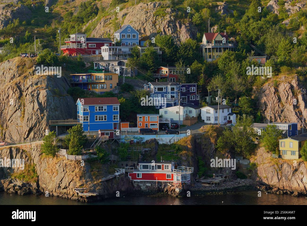 Colorful houses built on the rocky hillside along the harbor in St John ...