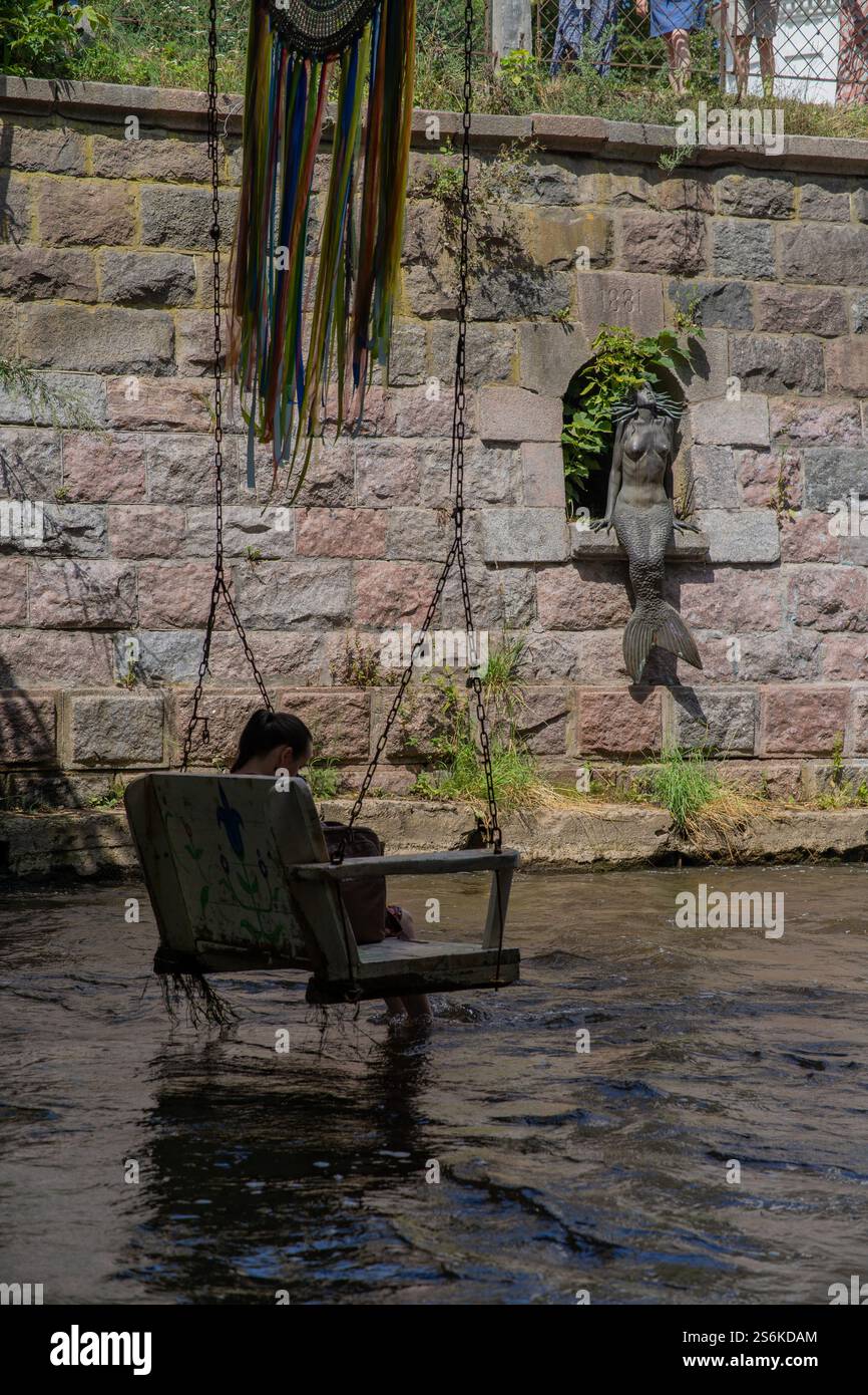 A tranquil riverside view featuring a colorful swing over the water and ...