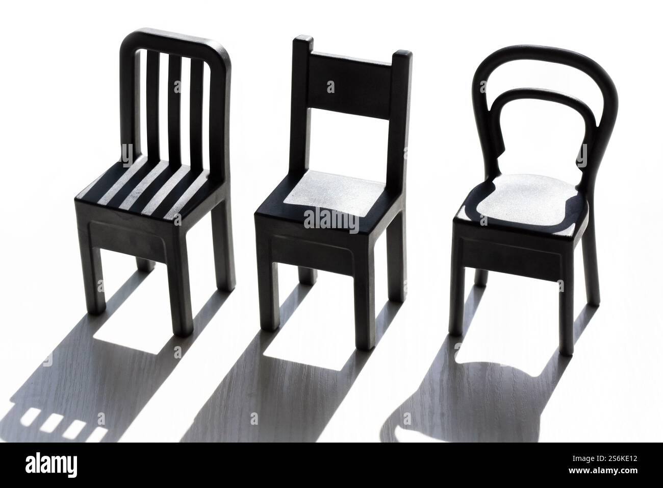 Three empty black chairs with shadow on white surface under sunlight ...