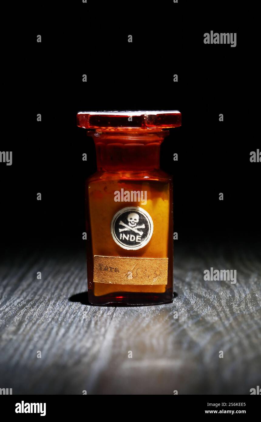 Old glass flask with poison under beam of light on dark background ...