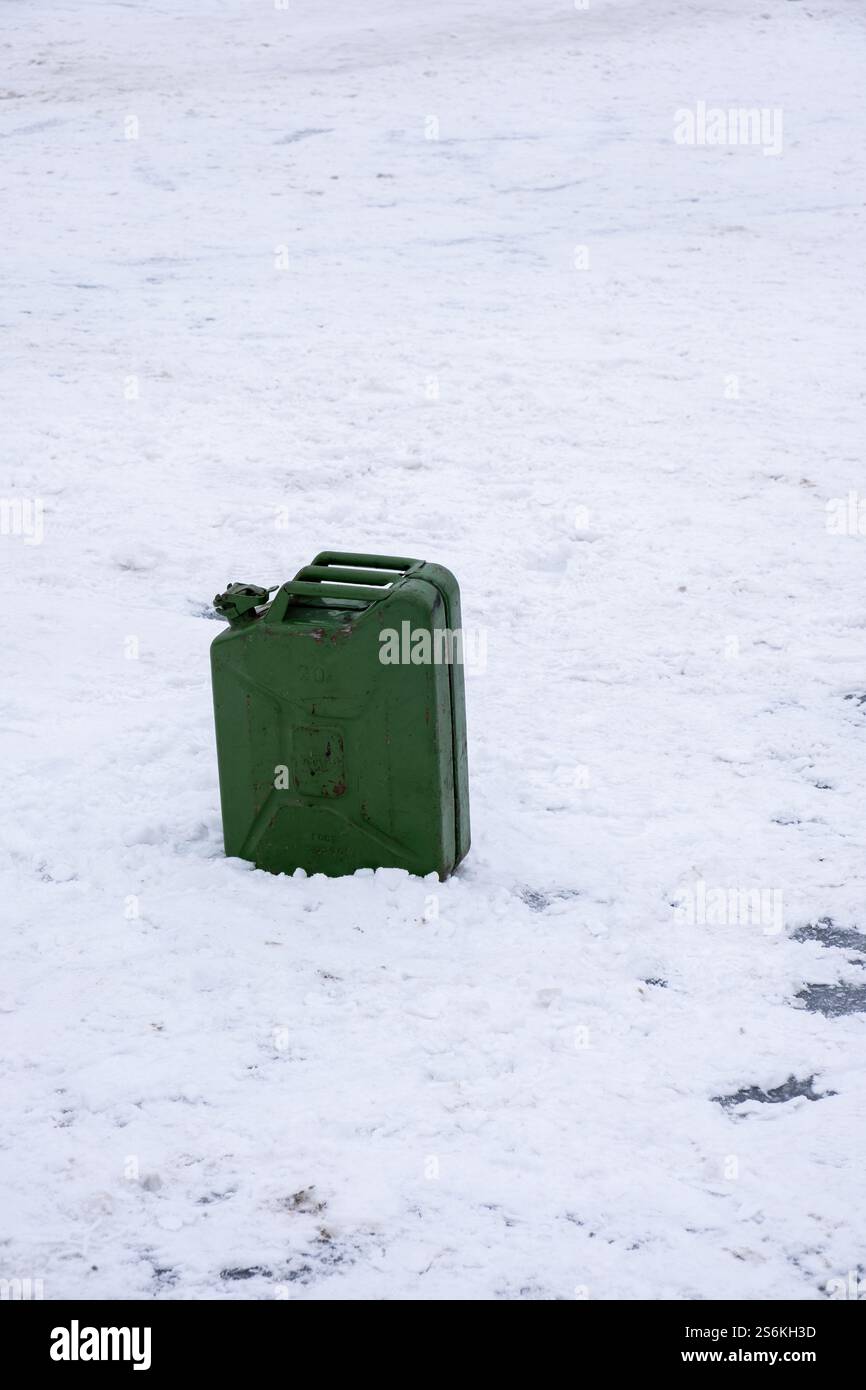 Green metal canister stands alone on snowy surface. Rust and signs ...