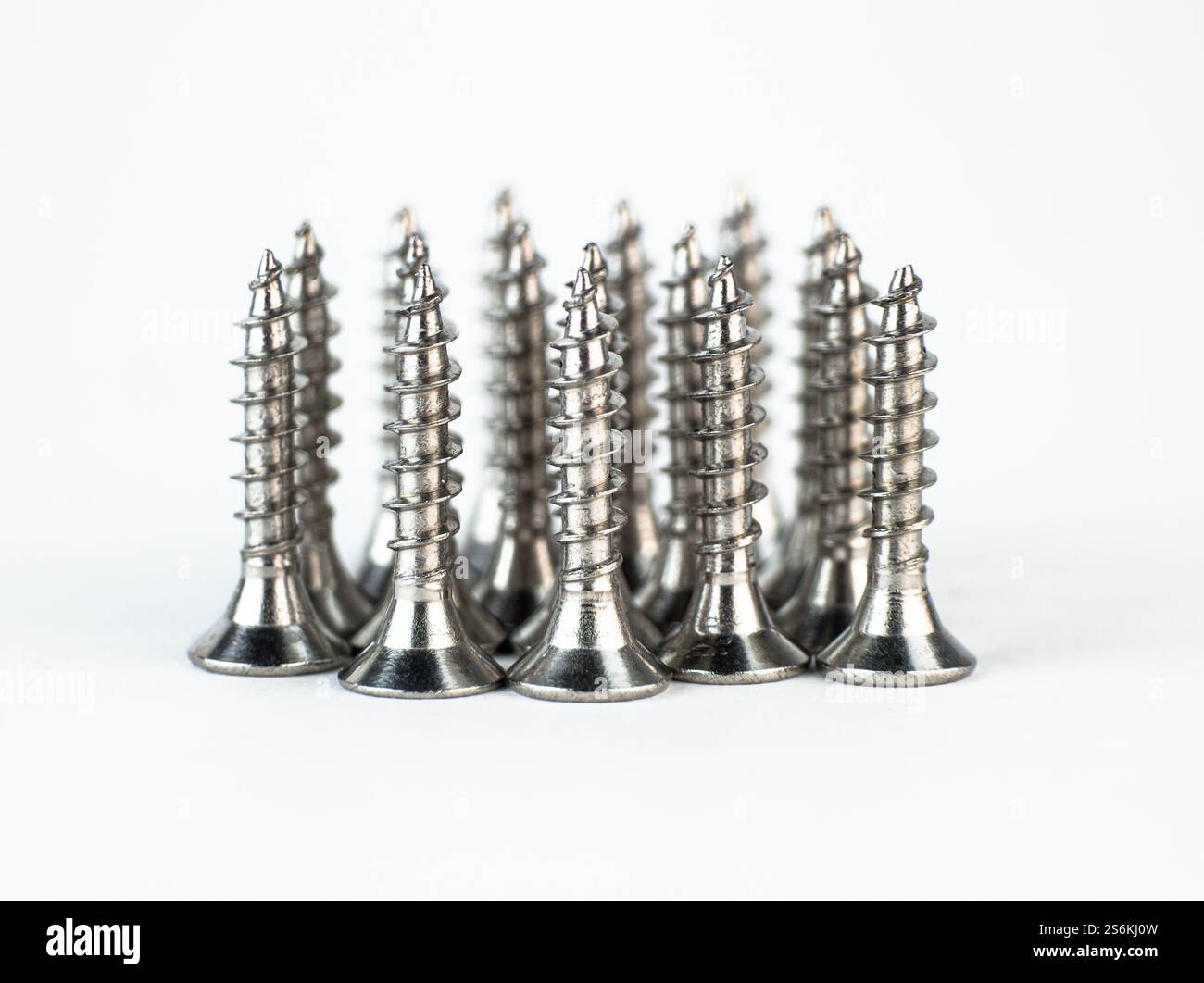 Screws made of silver-colored metal are stacked together in an orderly ...