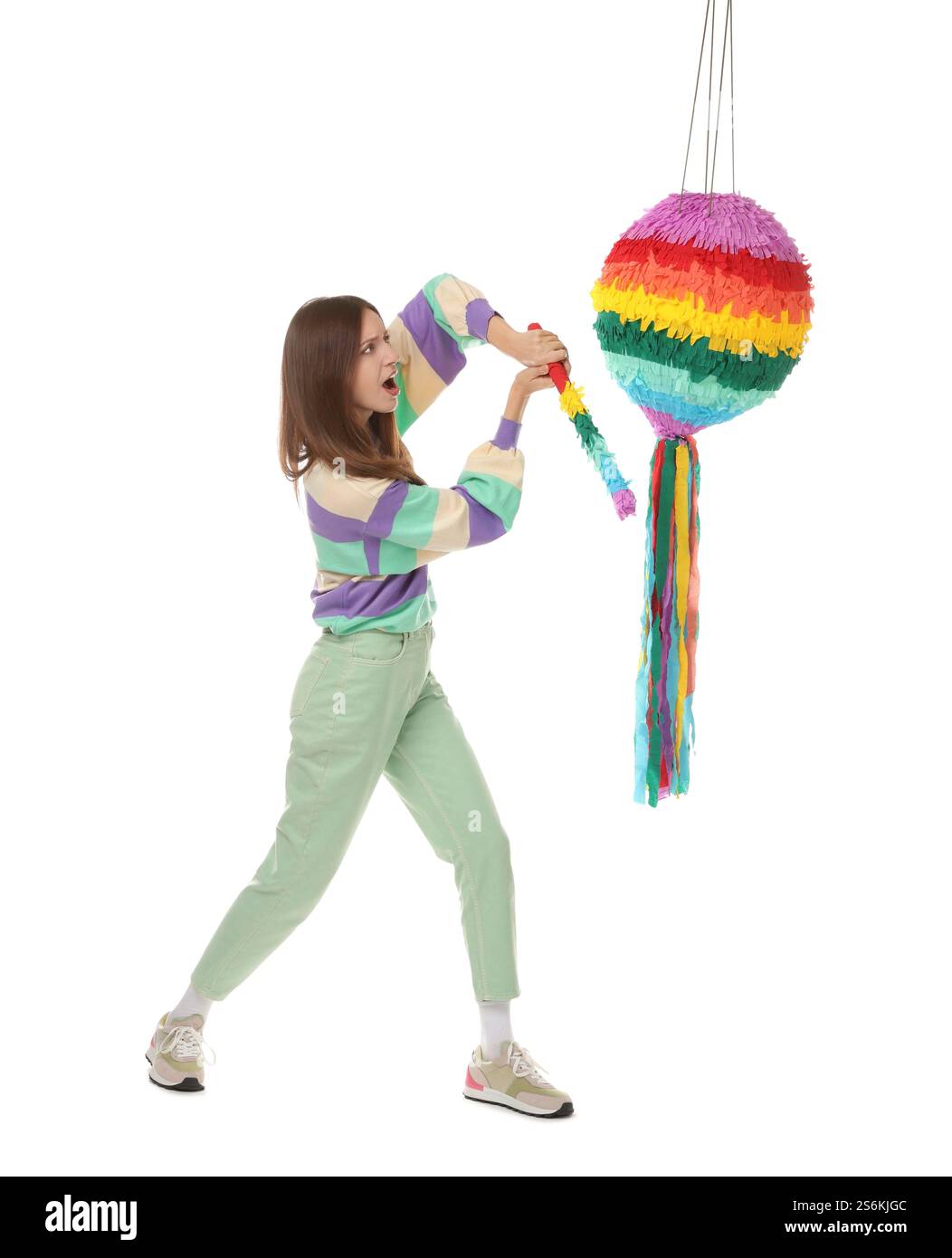 Emotional woman breaking colorful pinata with stick on white background ...