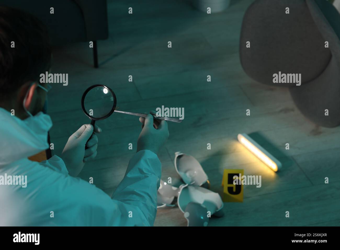 Forensic expert with tweezers examining hair through magnifying glass ...