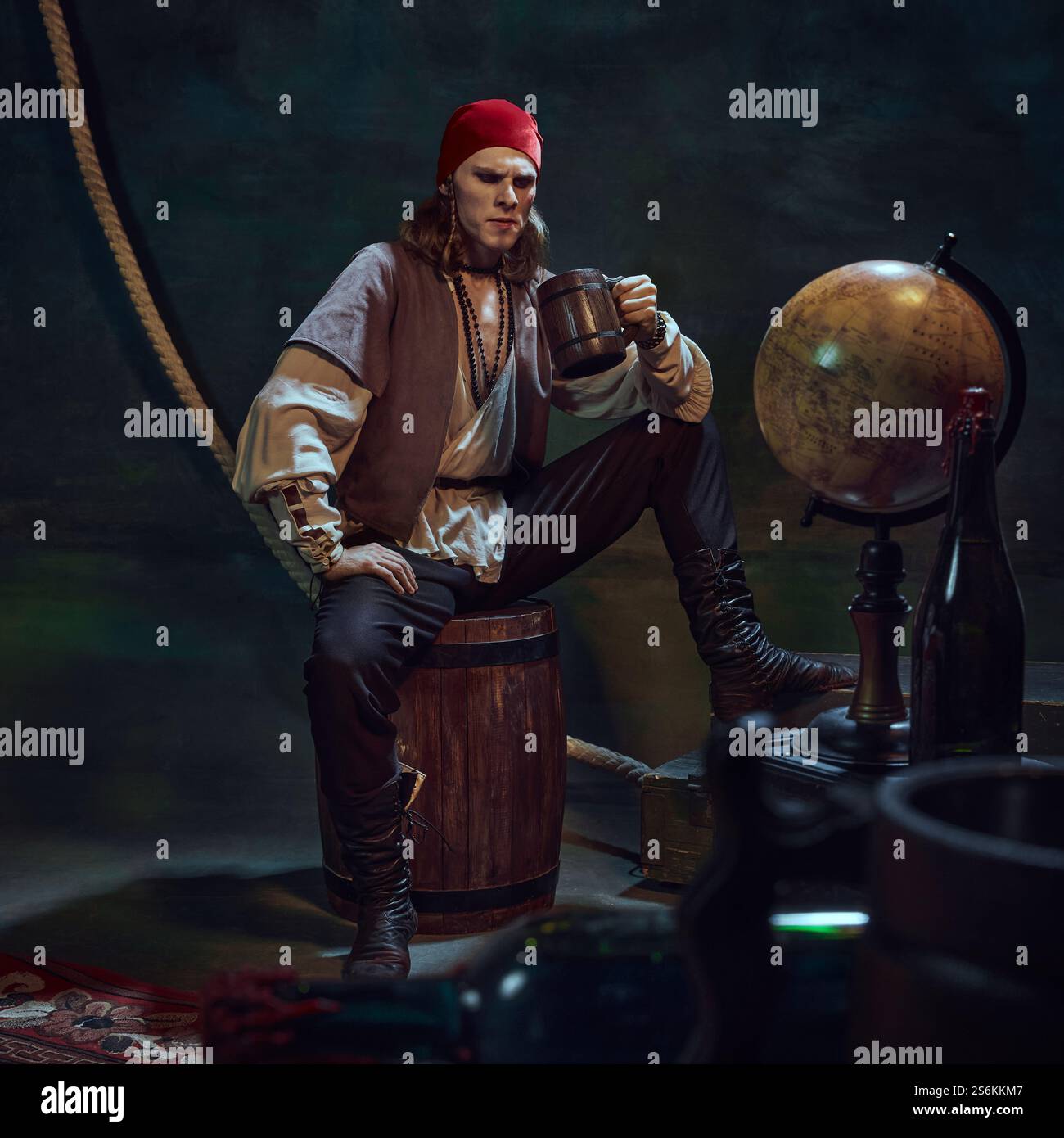 Young man, pirate dressed in traditional attire, sits on barrel, holds ...