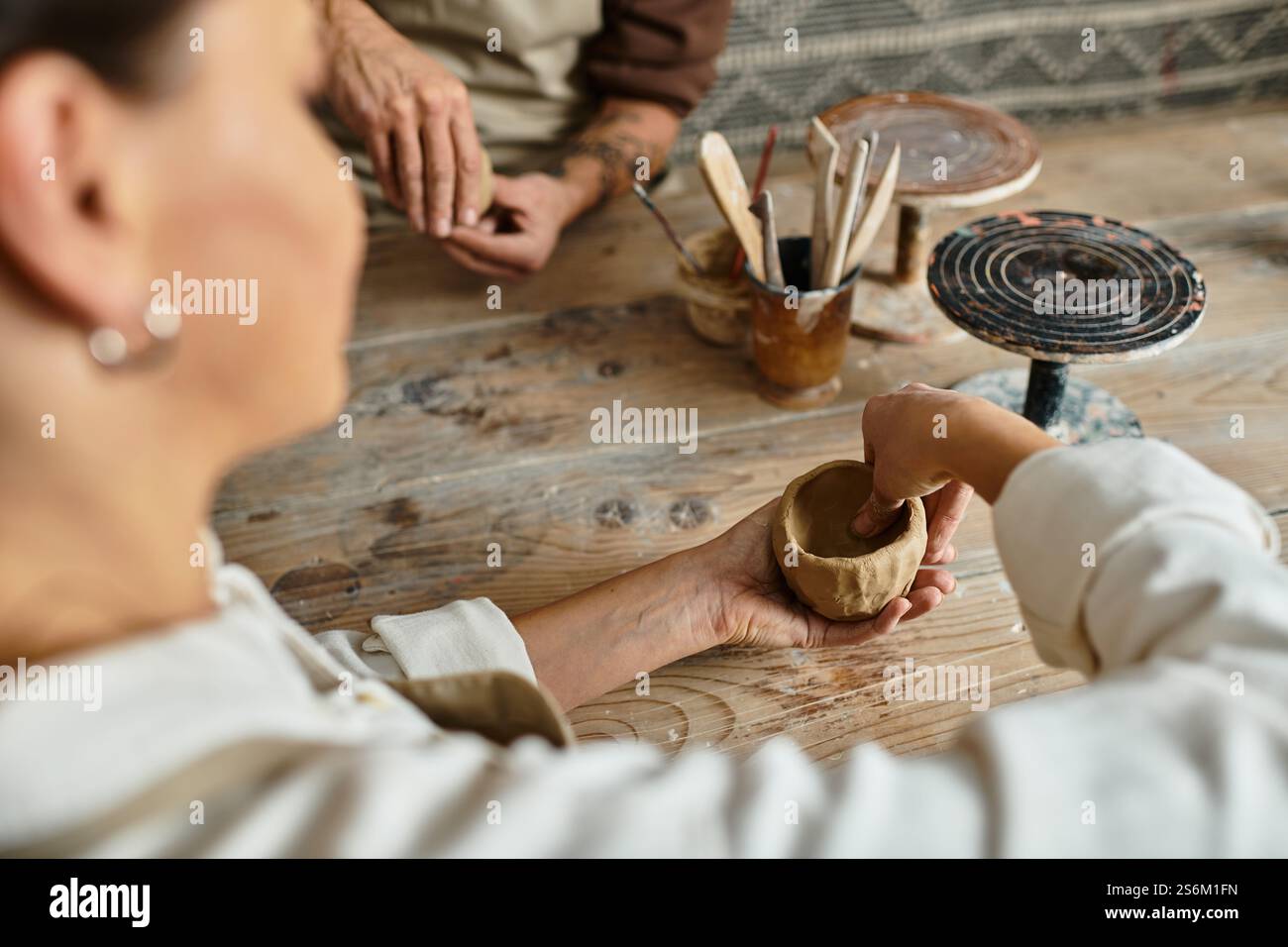 A mature couple enjoys shaping clay together during a pottery class ...