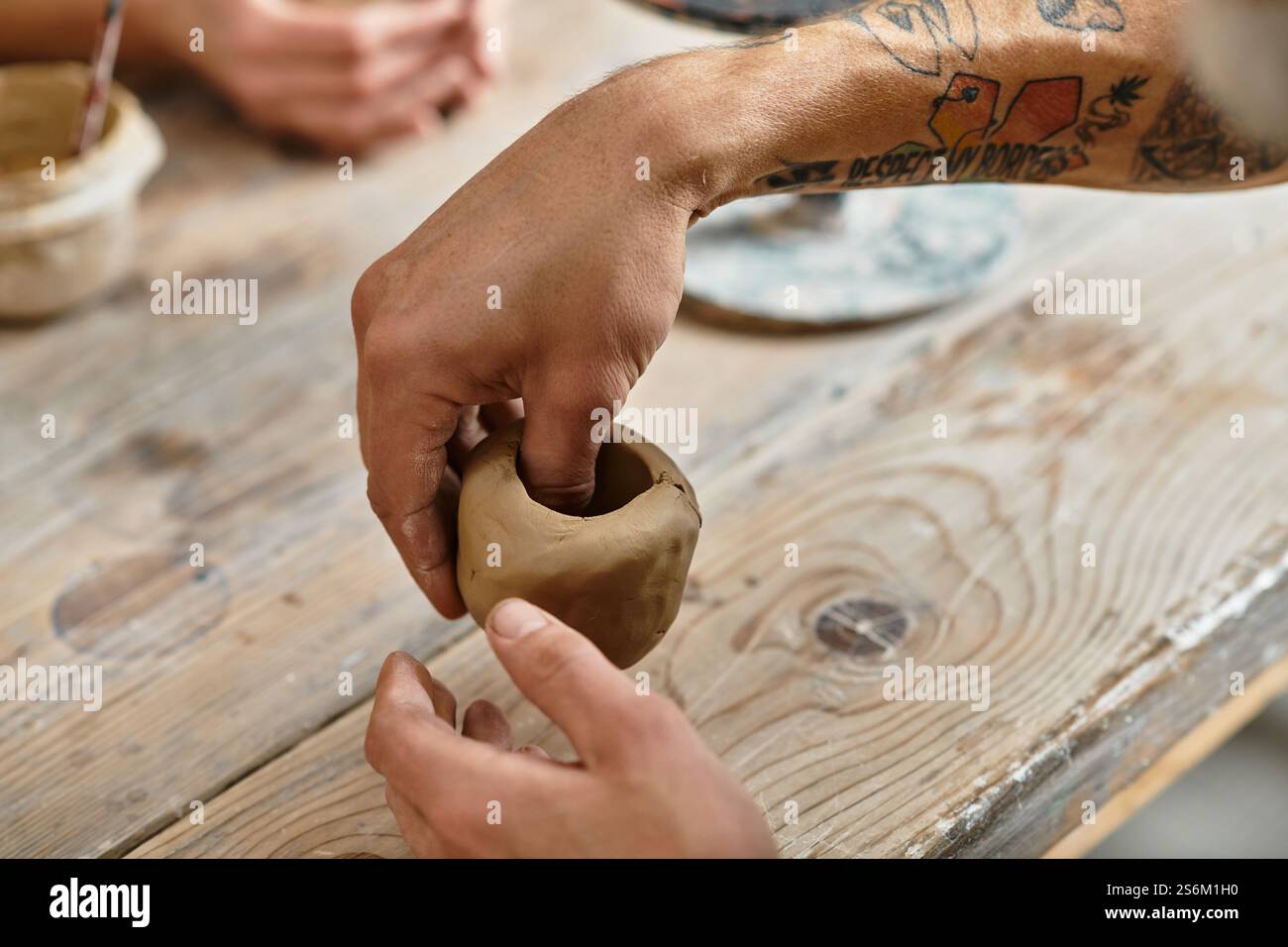 tattooed man shaping clay during pottery class Stock Photo - Alamy