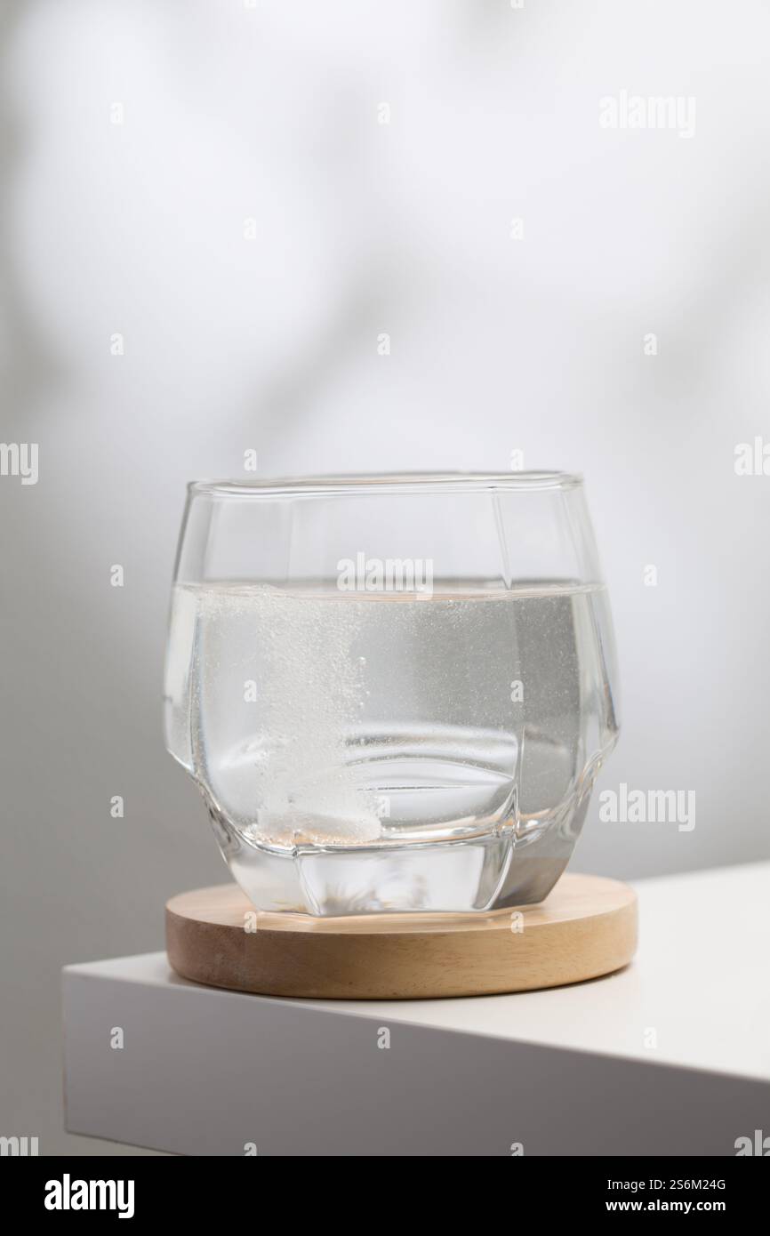 An effervescent mucolytic tablet dissolves in a glass of drinking water ...