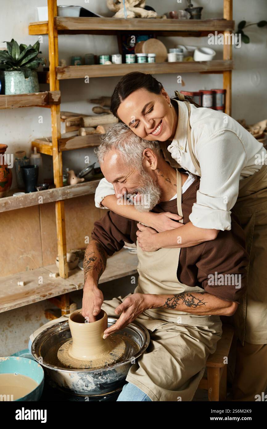 A beautiful couple shapes clay together in a pottery class, enjoying ...