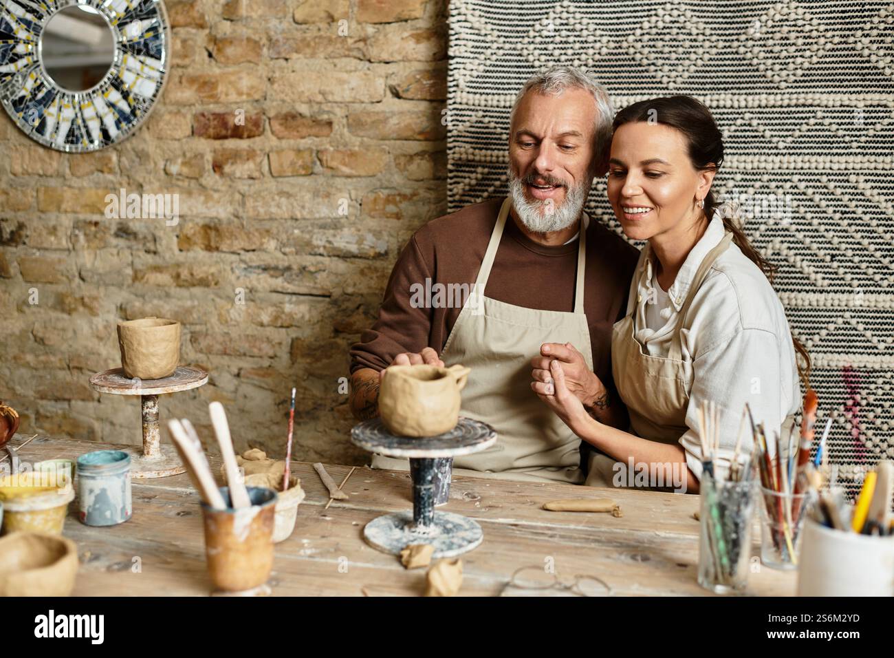 A mature couple enjoys shaping clay together during an engaging pottery ...