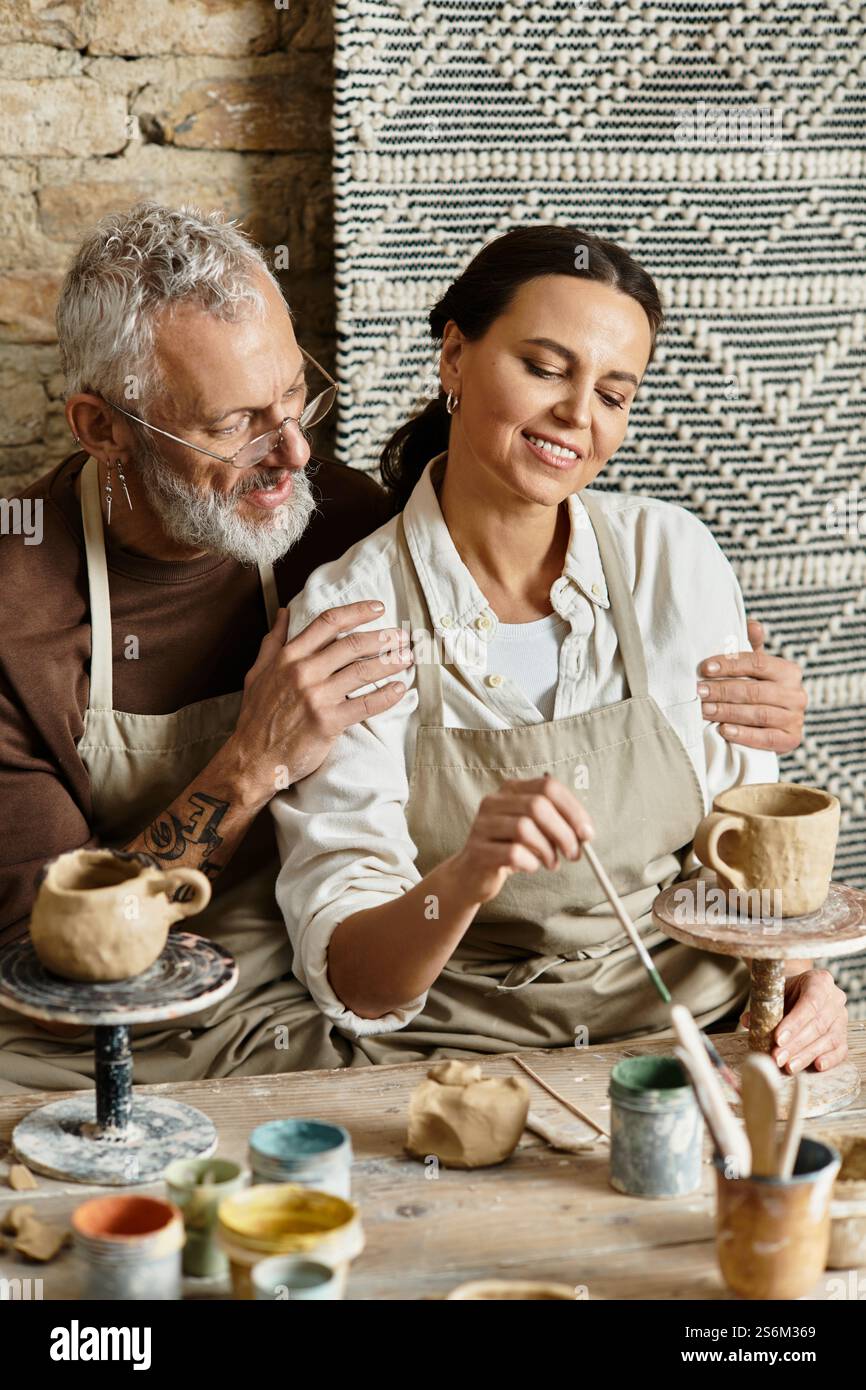 A beautiful mature couple shares a joyful moment shaping clay together ...