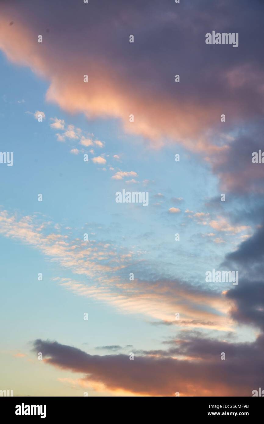 A calm sky with soft golden clouds illuminated by the setting sun. The ...