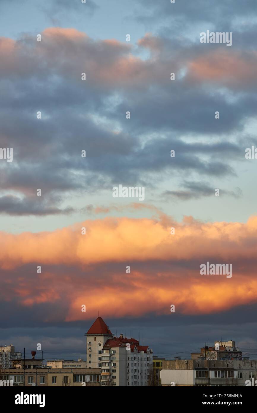 A vibrant sunset sky with dark clouds and orange highlights contrasts ...