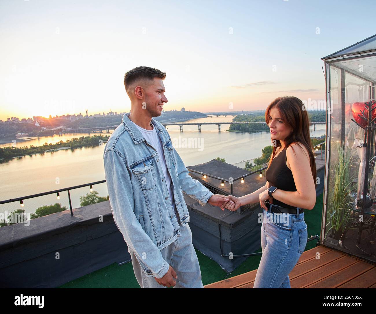 A young couple kisses and embraces during a romantic rooftop date, with ...