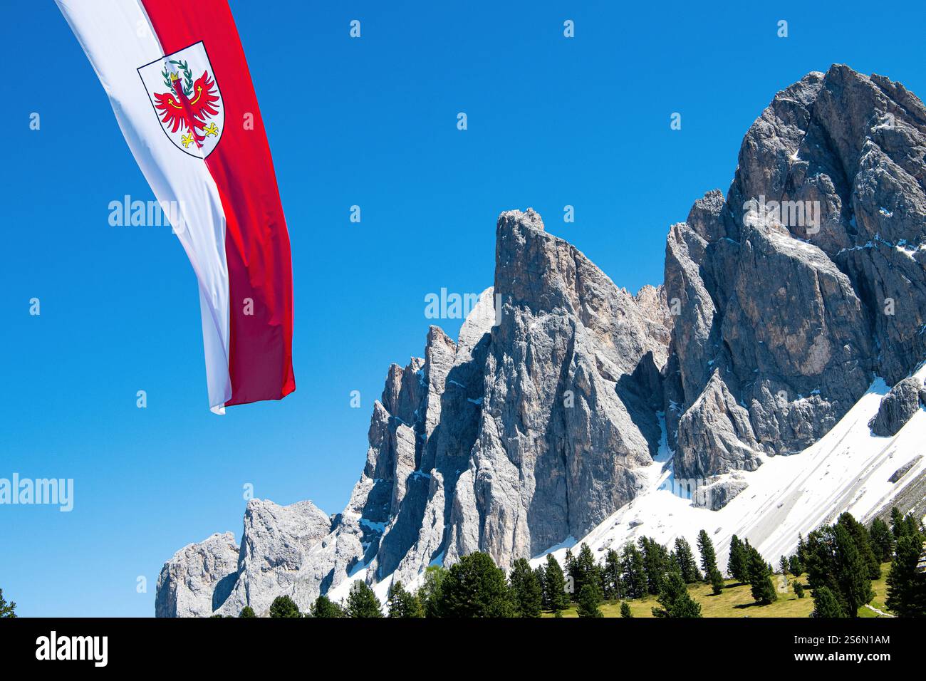 The Tyrolean flag with coat of arms against a blue sky and Dolomite ...