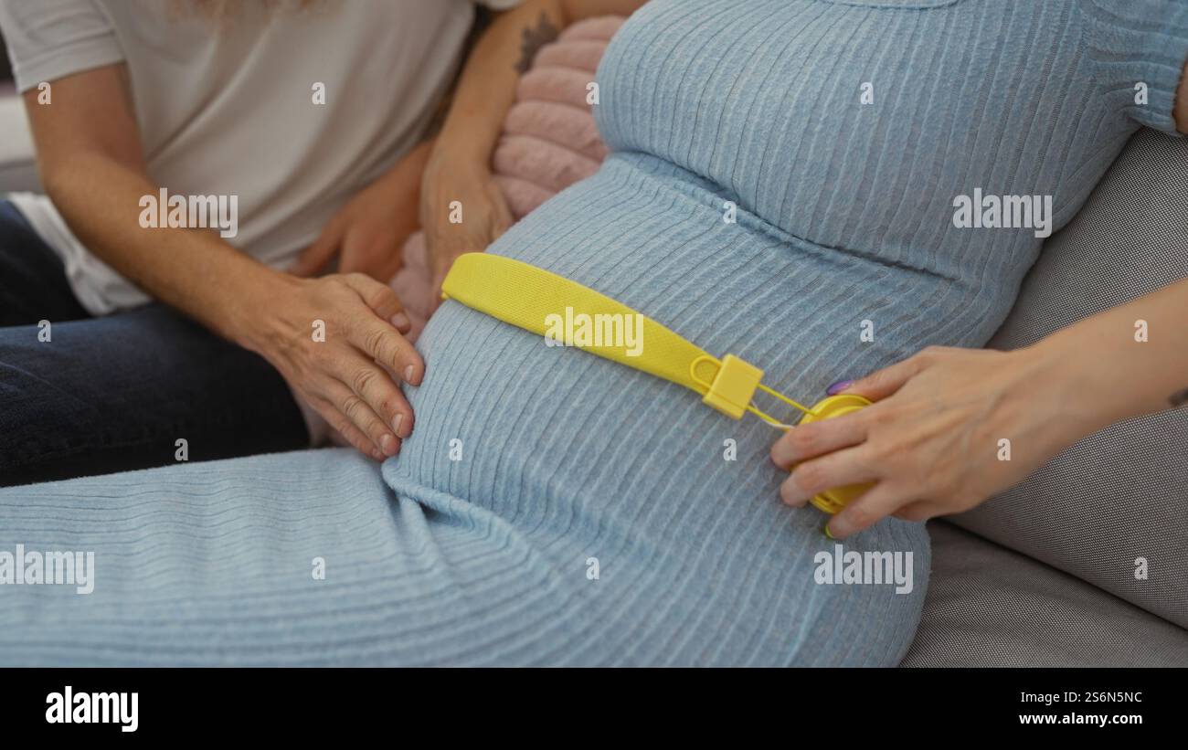 Couple at home with man touching pregnant woman's belly in the living ...