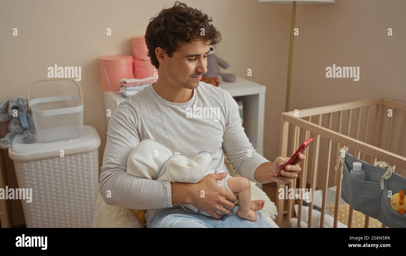 Young man holding baby indoors using smartphone by cradle in bedroom ...