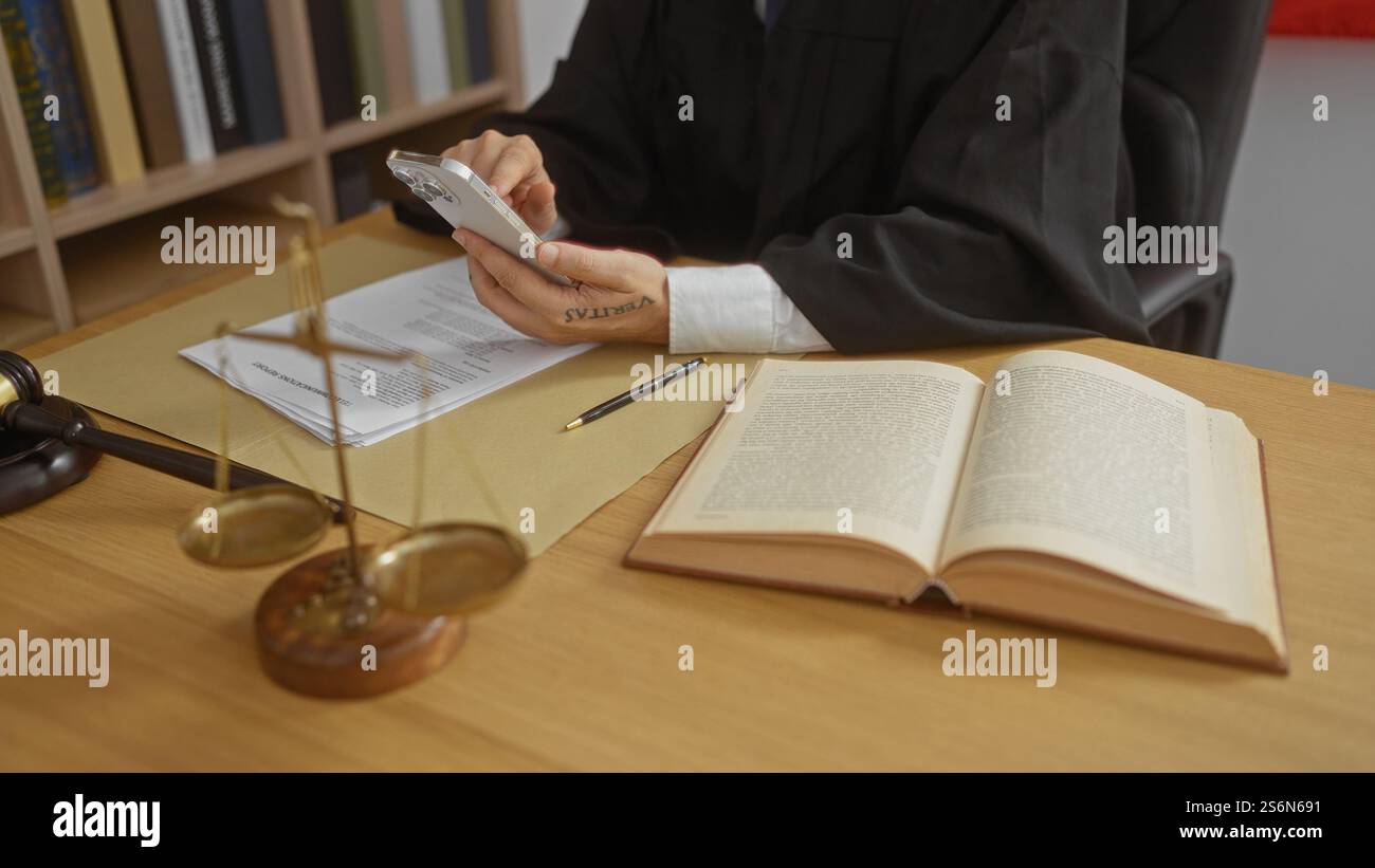 Judge seated at a desk in a courtroom using a smartphone with a gavel ...