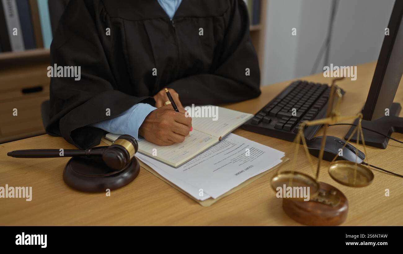 Female judge in an office writing in a notebook with a gavel and scales ...
