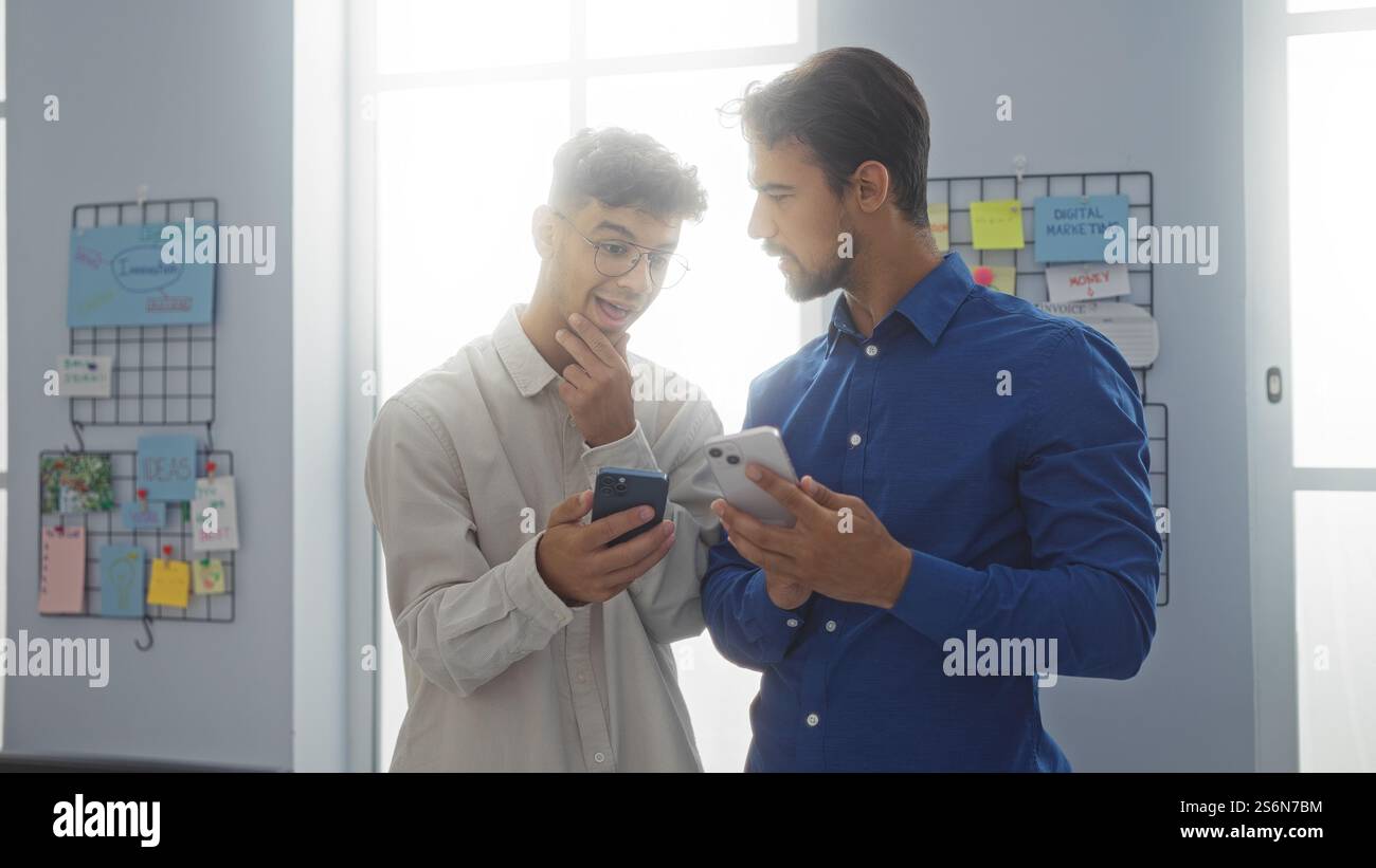 Men discussing over mobile phones in a modern office setting conveying ...