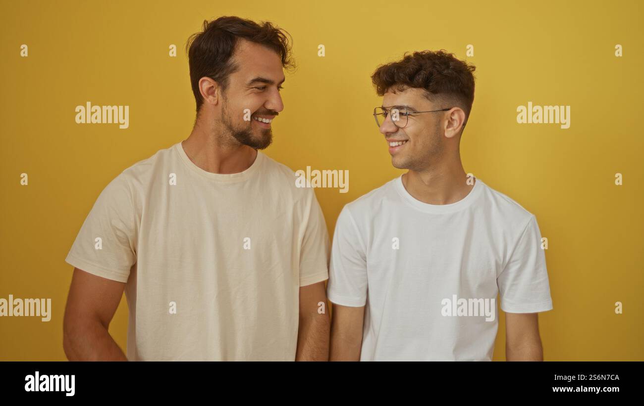 Father and son standing together against a yellow background, sharing a ...