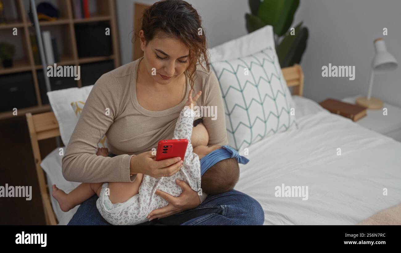 Mother breastfeeding baby while sitting on bed in cozy bedroom ...