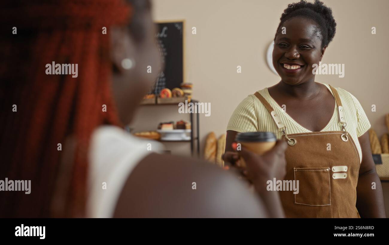 Two african american women interacting in a bakery with one as an ...