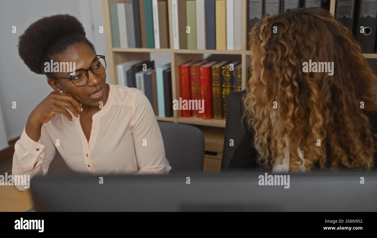 Two women business partners talking together in an office workplace ...