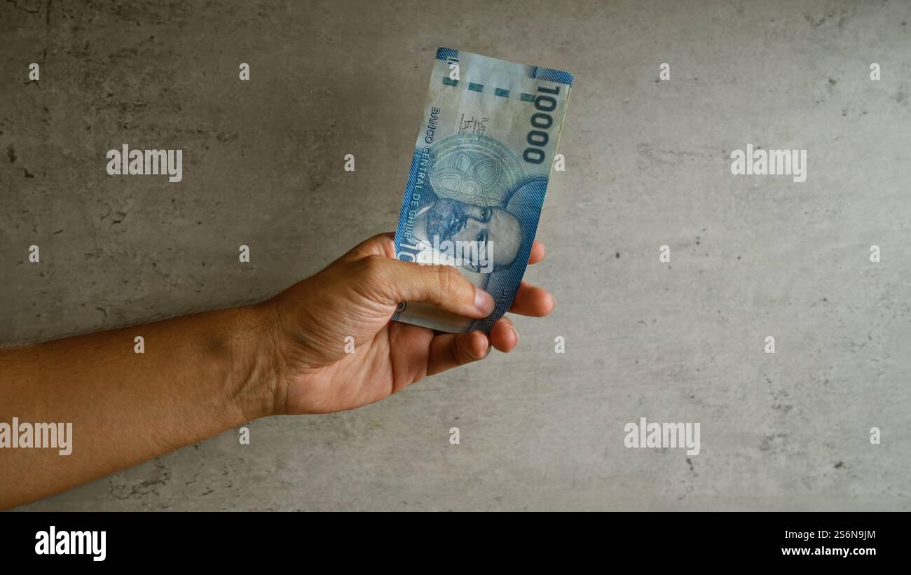 Hand holding chilean pesos against a concrete background, showcasing ...
