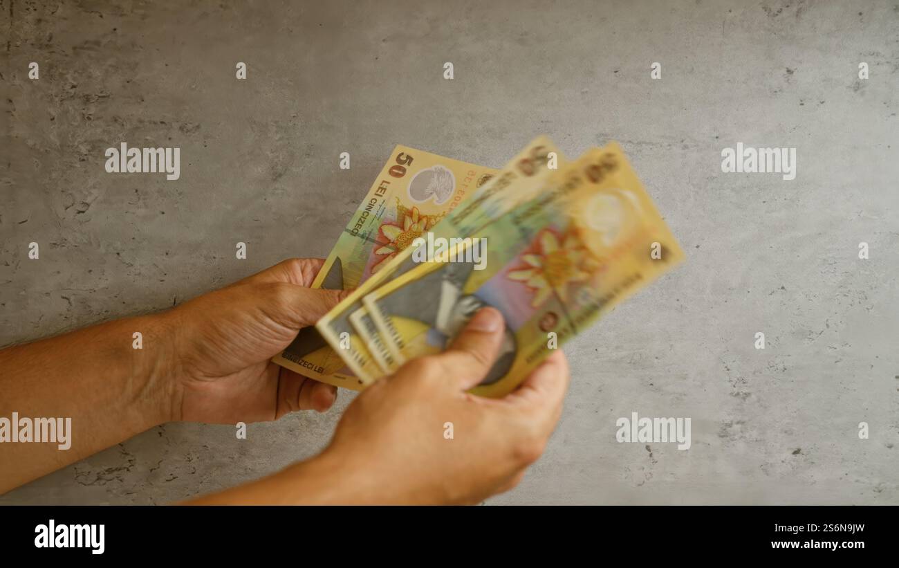 Hands holding romanian lei banknotes against a concrete background ...