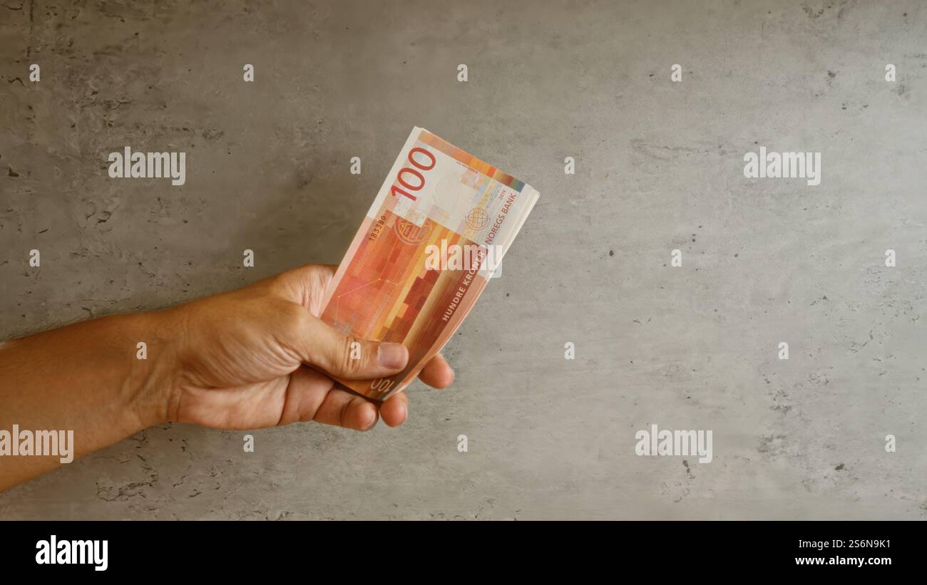 Hand holding norwegian 100 krone bill against a concrete wall Stock ...