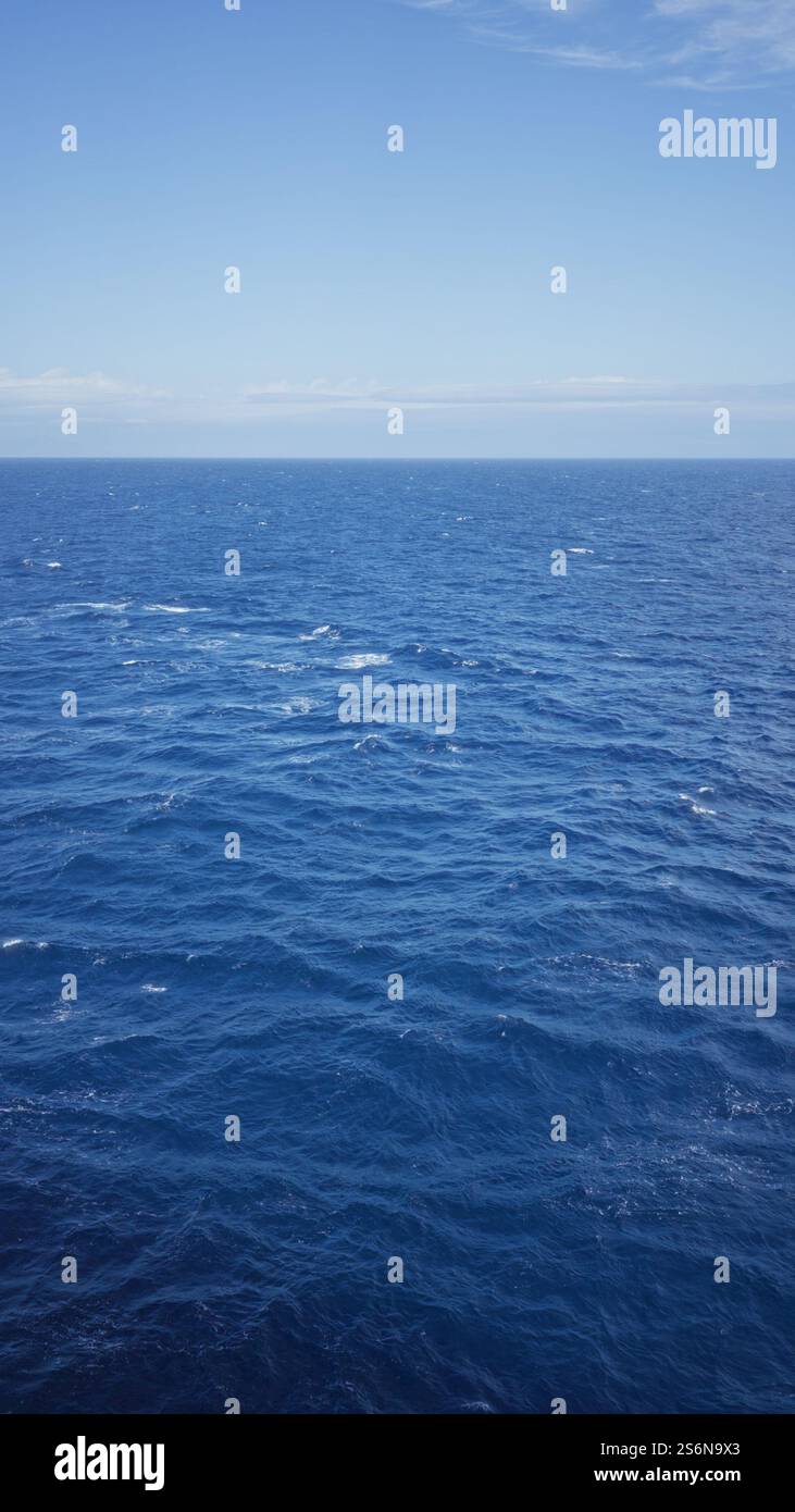 Expansive ocean waves shimmer under a bright blue sky depicting an ...