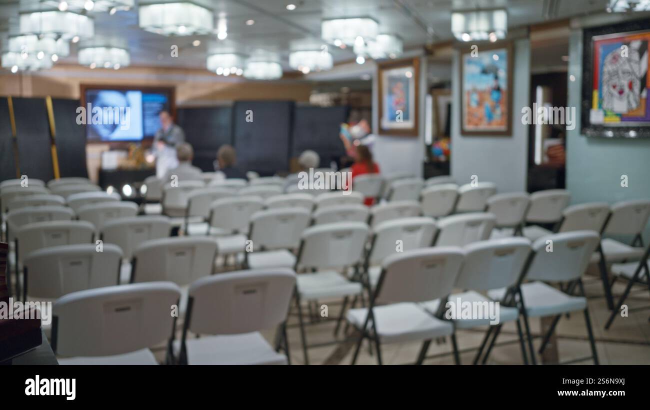 Blurred image shows spacious art gallery with chairs and paintings ...