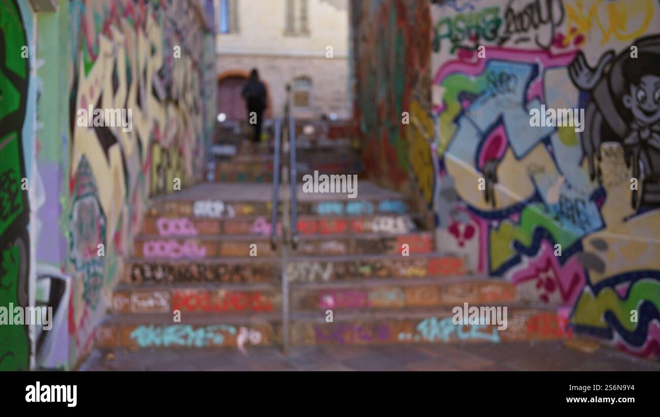 Man walking up graffiti-covered steps in an urban street with blurred ...